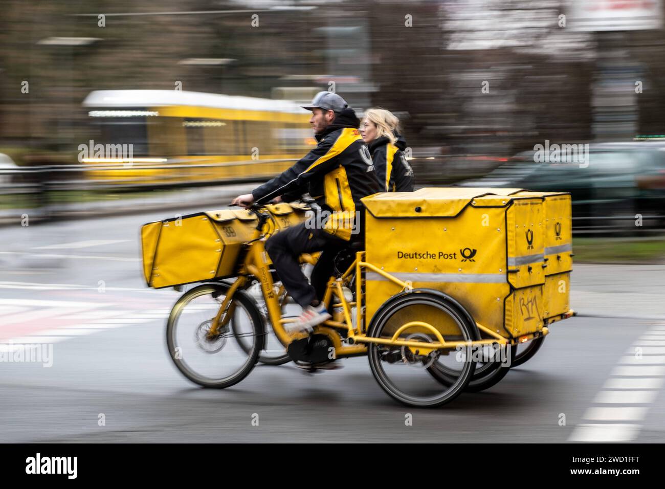 Zwei Briefträger der Deutschen Post fahren mit ihren Lastenfahrrädern ...