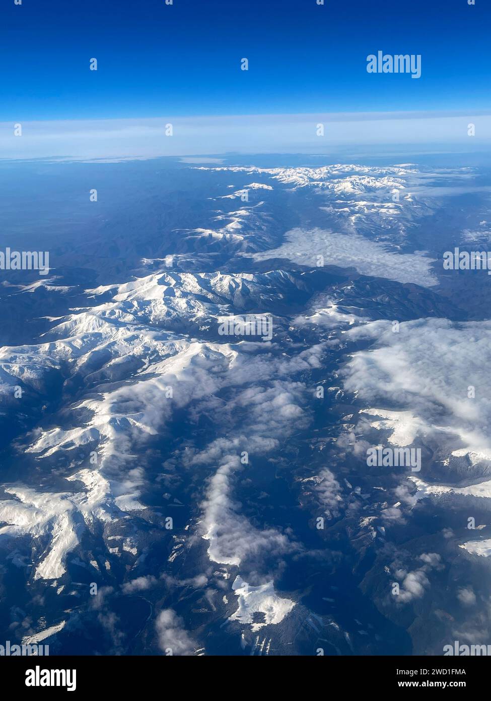 Stunning aerial shot capturing snow-covered peaks and wispy clouds ...