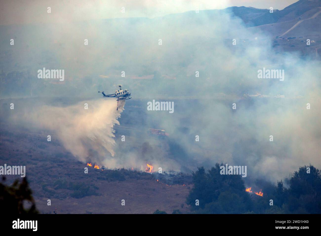 A Bell 205 A1 fire and rescue helicopter drops water in an effort to ...