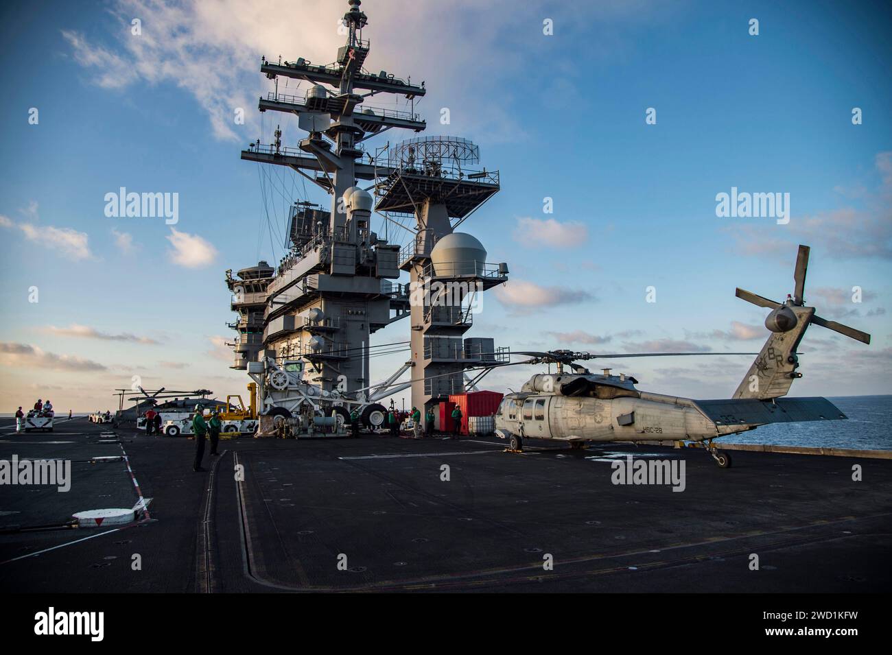 Sailors stand by as an MH-60S Sea Hawk prepares to take off from the ...