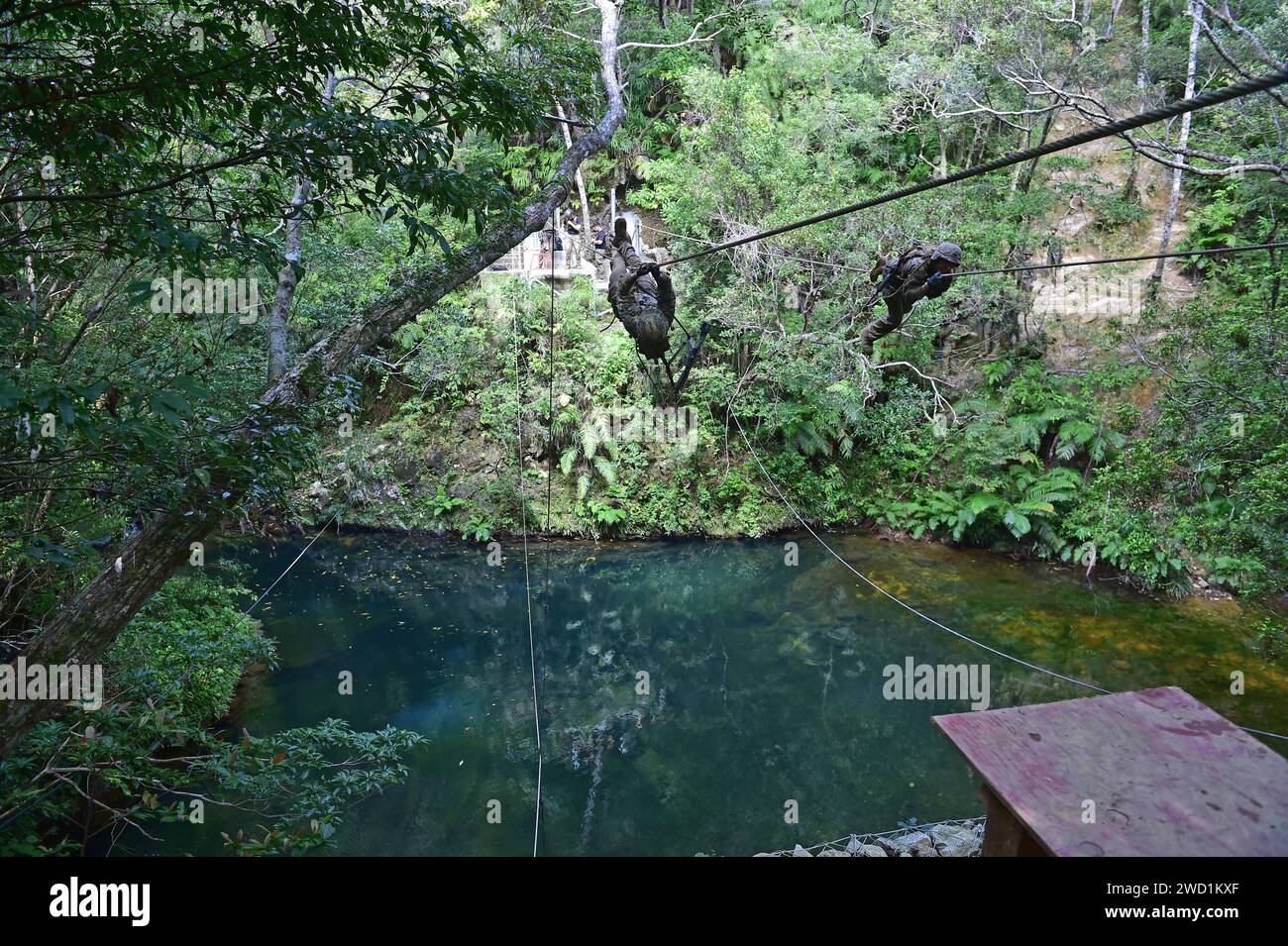 Seabees crawl across a wire obstacle at the Jungle Warfare Training ...