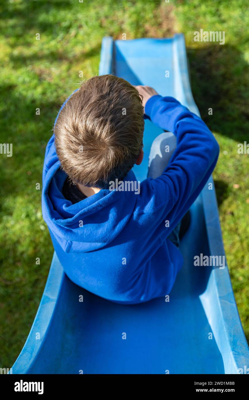boy sitting on blue slide Stock Photo - Alamy