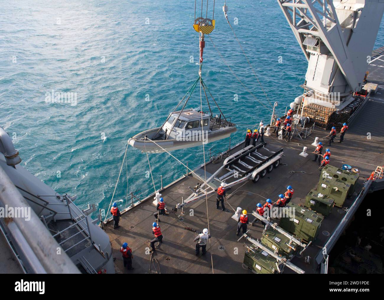 Sailors lower a rigid-hull inflatable boat from the amphibious dock ...