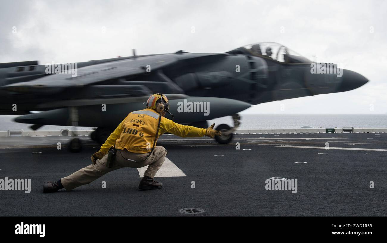 Aviation Boatswain's Mate signals to an AV-8B Harrier as it launches ...