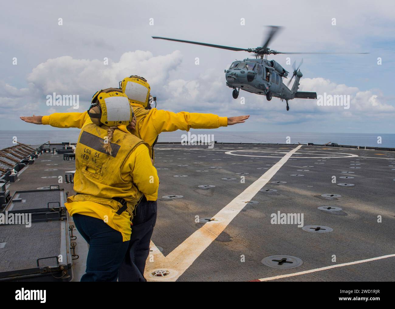 Airmen signal to an MH-60S Sea Hawk helicopter as it lands on the ...
