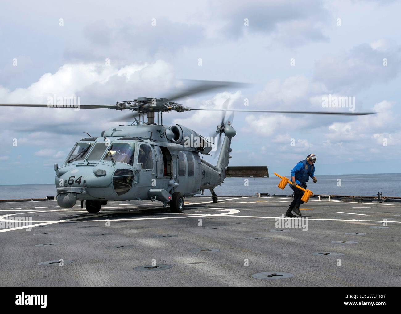 Boatswain's Mate pulls chocks from an MH-60S Sea Hawk helicopter on the ...