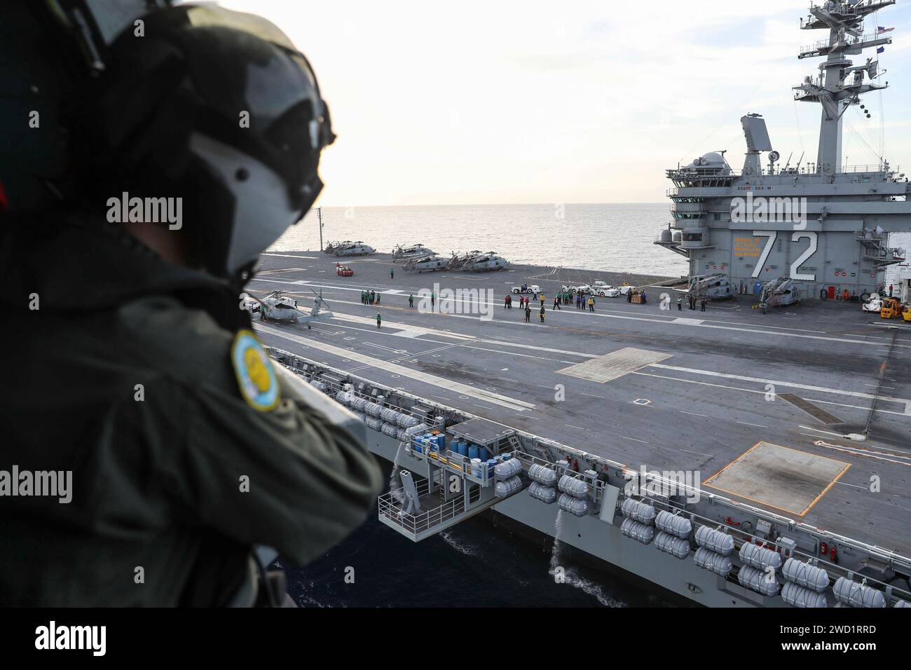 Naval Aircrewman looks out the door of an MH-60R Sea Hawk helicopter ...