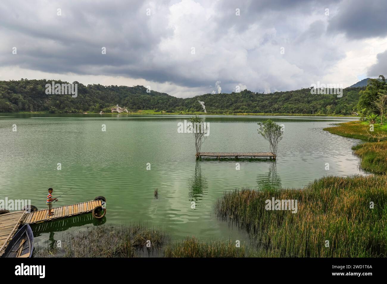 Boy fishing on dock by Lake Linow, a popular volcanic sight ...