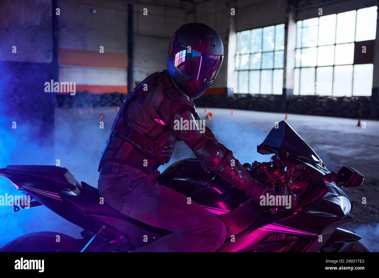 Portrait of motor biker wearing protective gear and helmet in neon ...