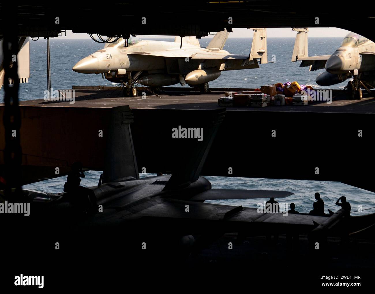 Sailors standby to unload mail from an aircraft elevator in the hangar ...