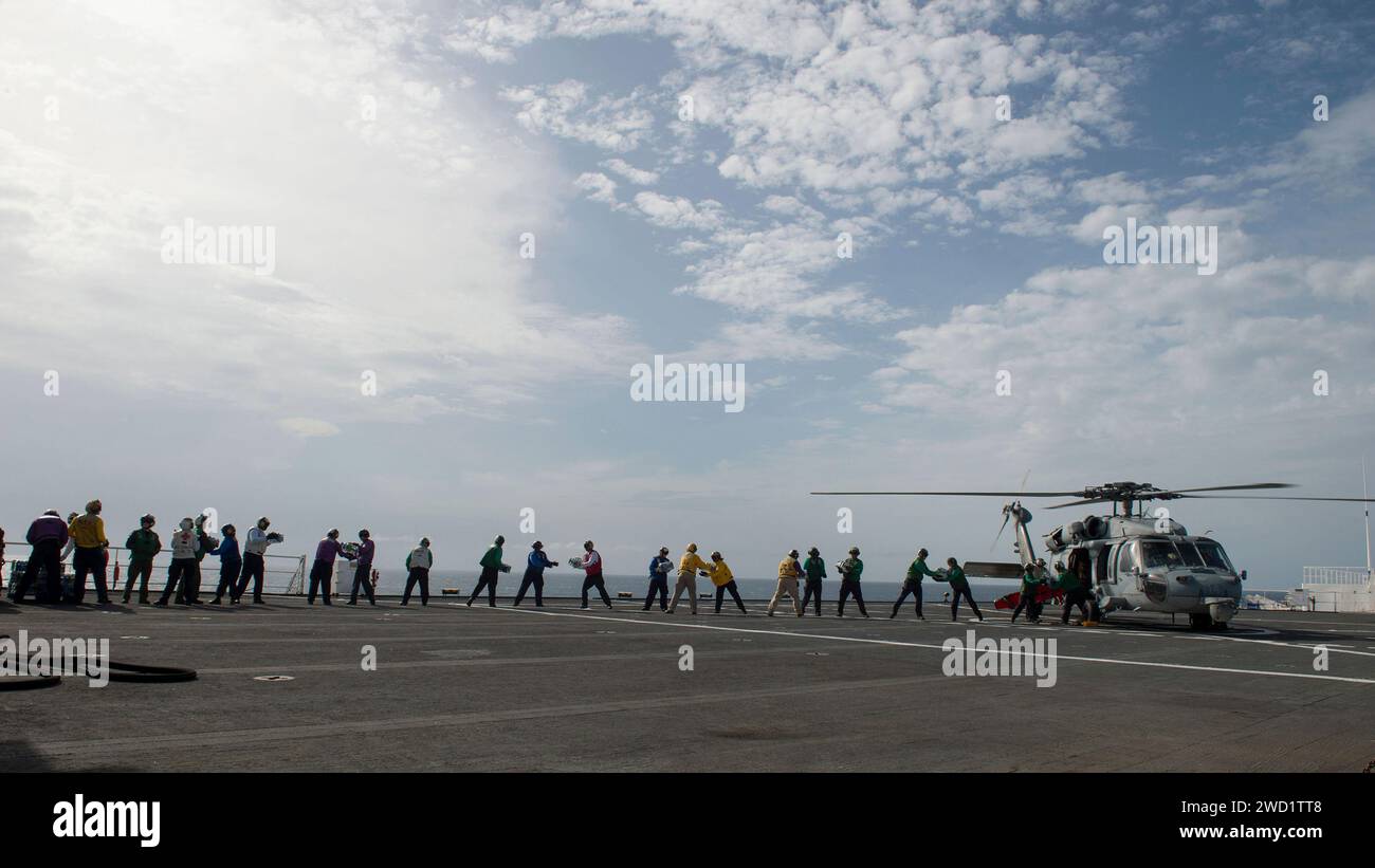Sailors load water onto an MH-60S Sea Hawk helicopter aboard the U.S ...