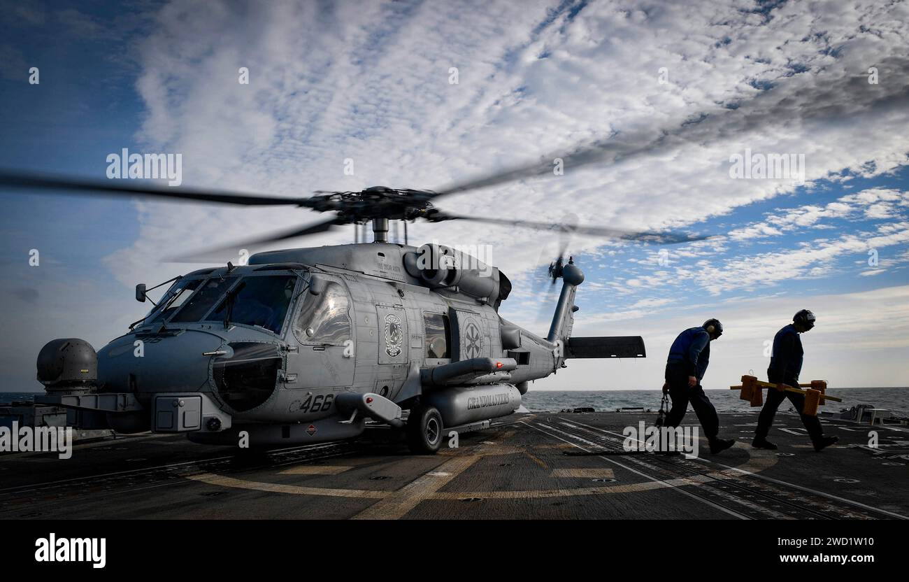 Sailors remove chocks and chains from an MH-60R Sea Hawk helicopter ...