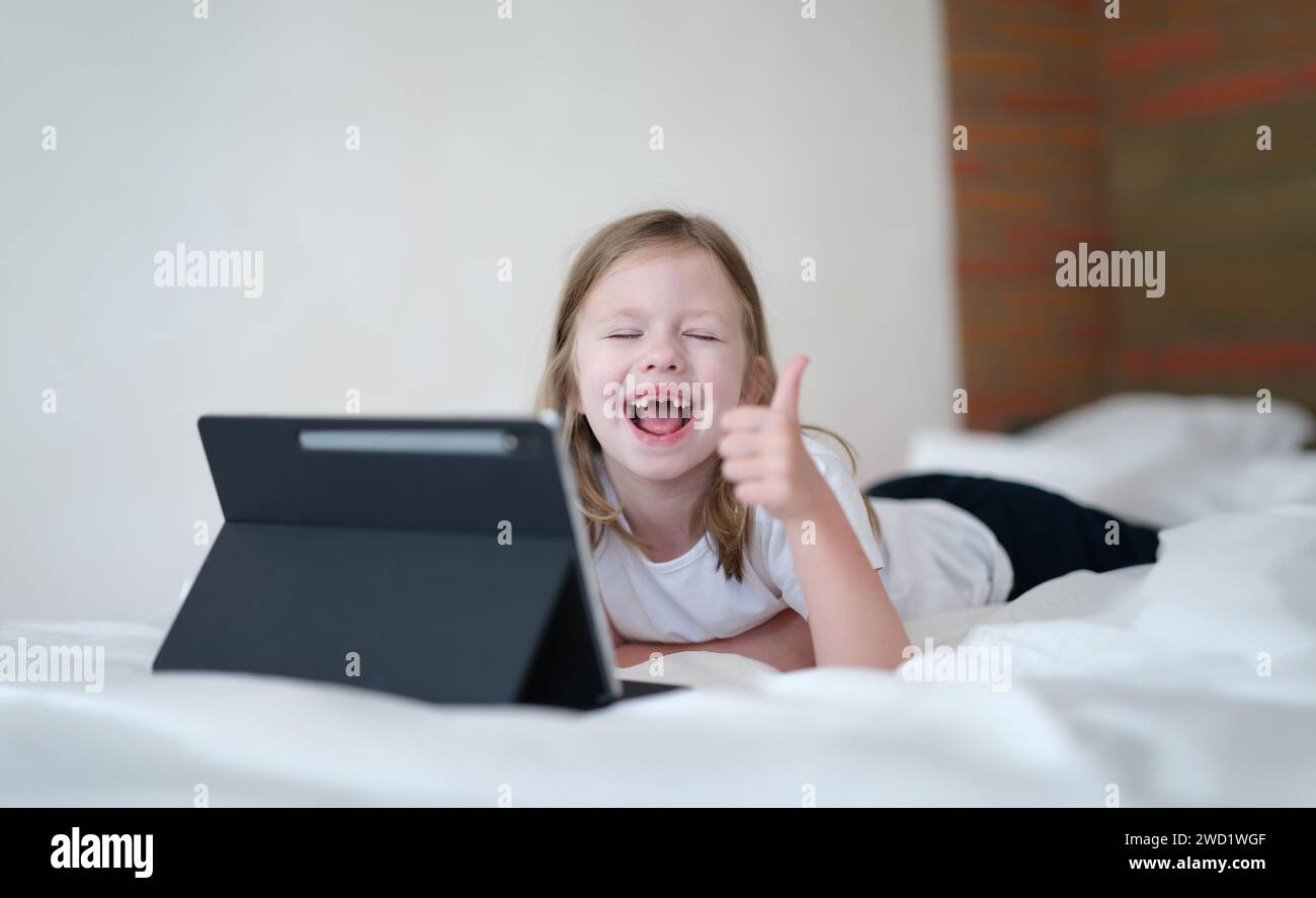 Happy baby girl holding thumbs up with tablet Stock Photo - Alamy