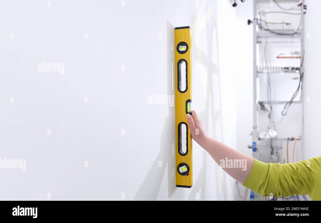 Builder hand with building level measures wall Stock Photo - Alamy