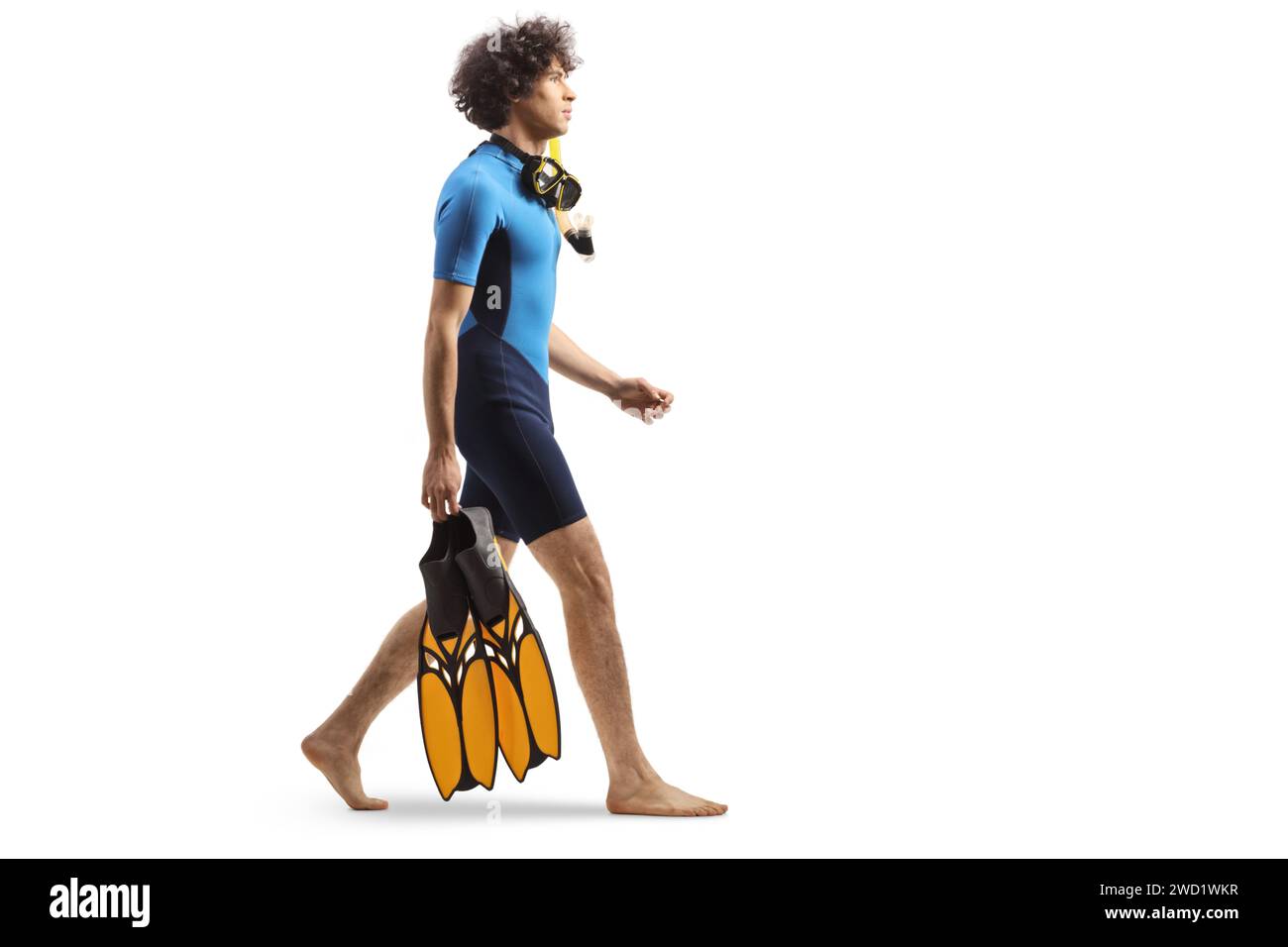 Full length profile shot of a guy in a diving suit carrying fins and ...