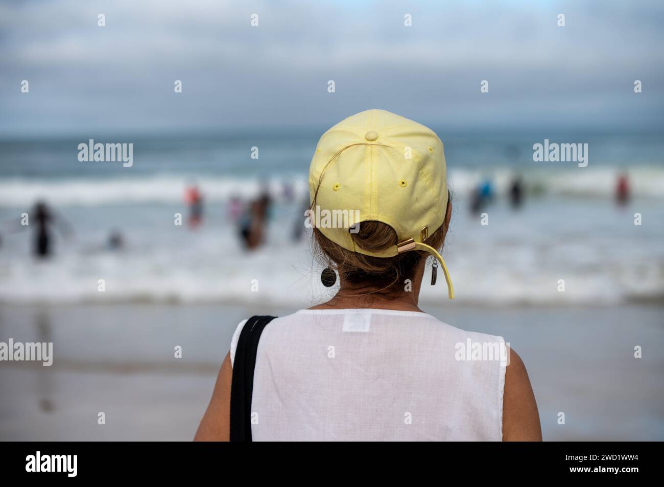 Woman seen staring at crowd at the beach Stock Photo - Alamy