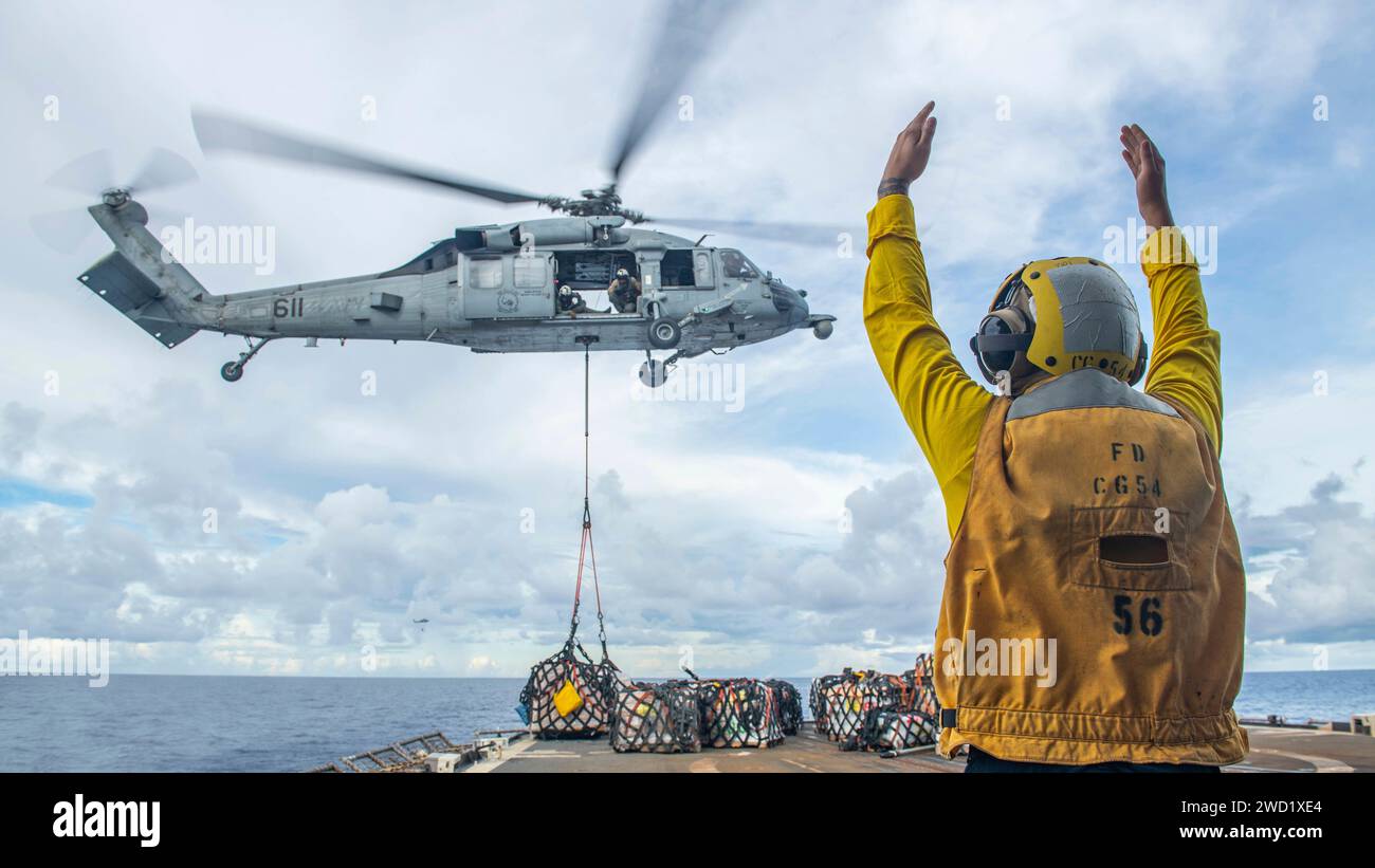 Gunner's Mate directs an MH-60S Sea Hawk helicopter as it drops cargo ...