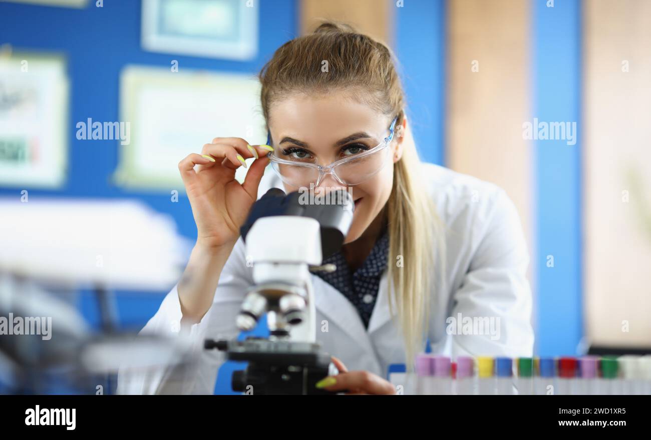 Clever laboratory lady in medical gown investigate sample under ...