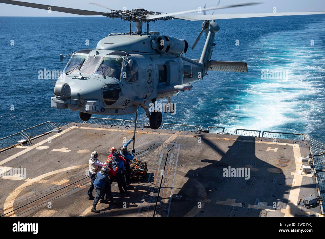Sailors attach a cargo pendant to an MH-60R Sea Hawk helicopter on the ...
