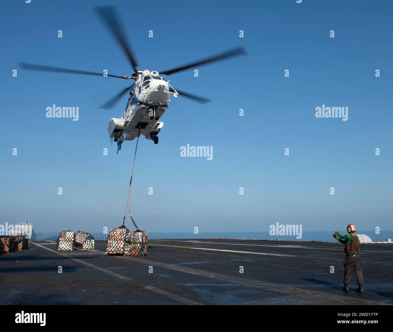 A Sailor signals a Super Puma (EC-225) helicopter on the flight deck of ...
