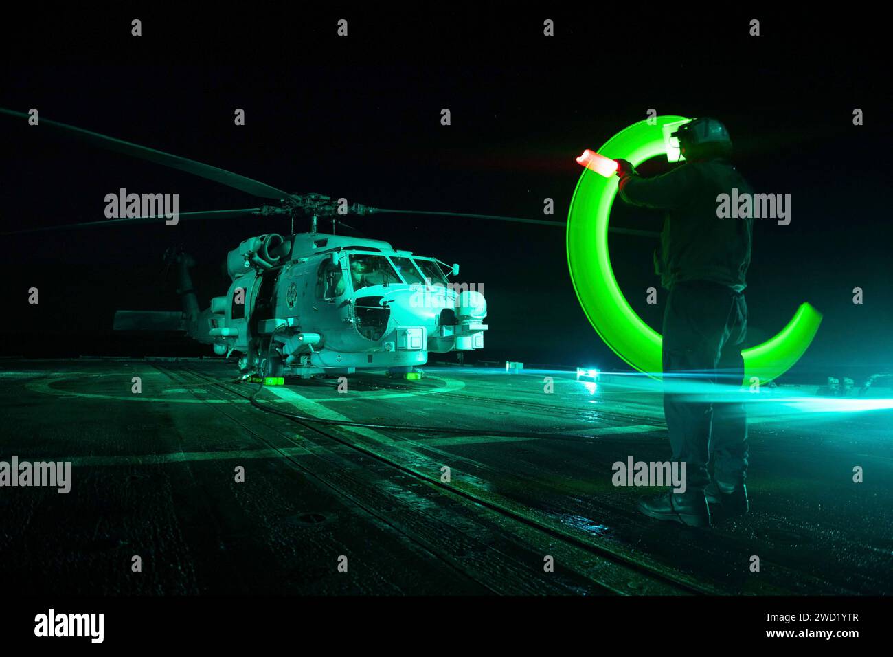 Airman signals the pilots of an MH-60R Sea Hawk helicopter on the ...