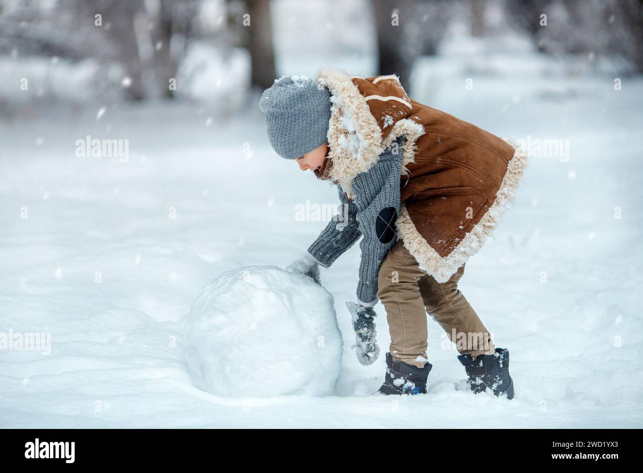 Boy is rolling snow ball for making a snowman Stock Photo - Alamy