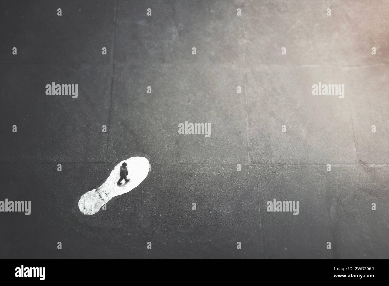 man follows the path of a surreal giant footprint on the street Stock ...