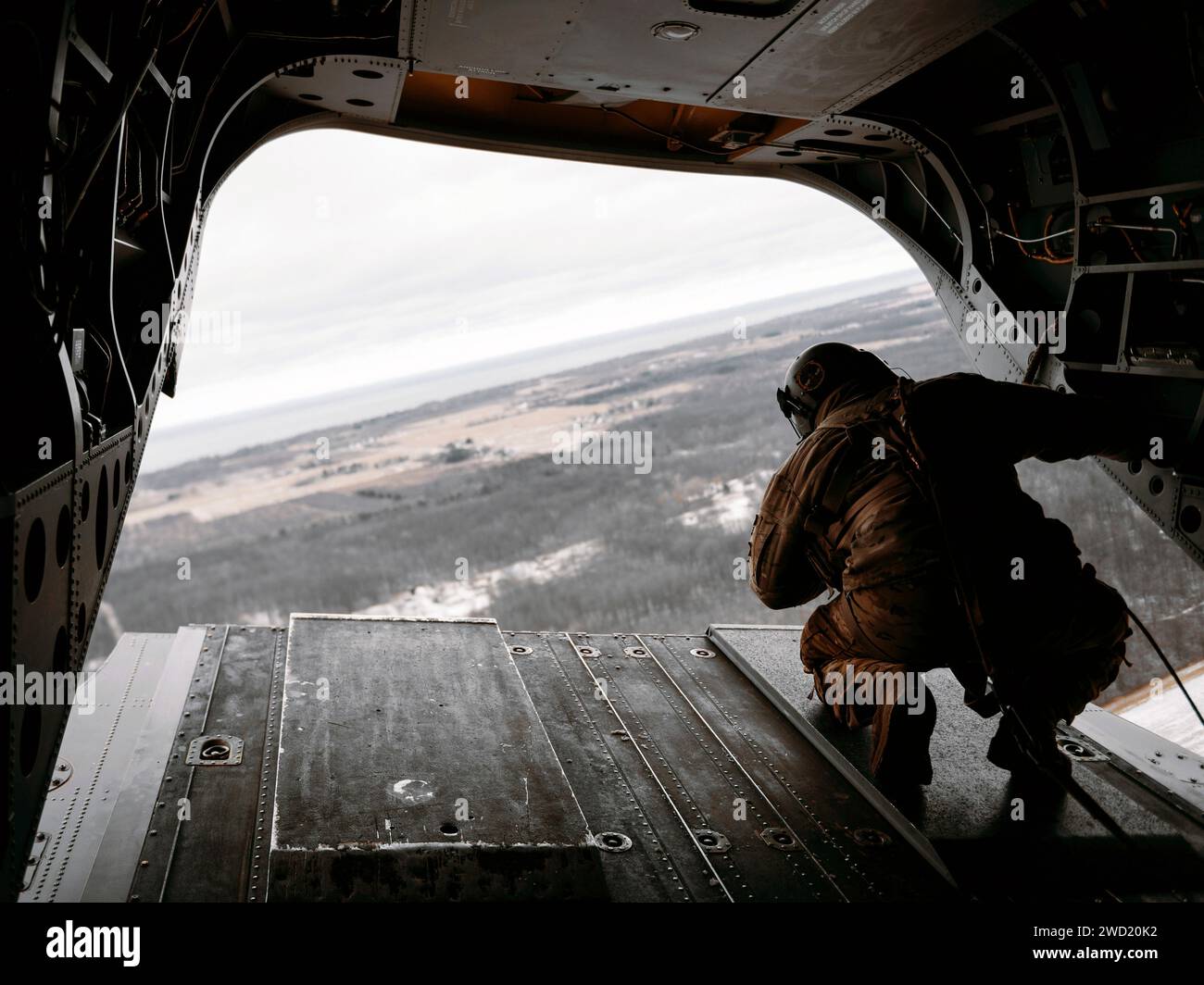 Crew chief checks the ground below the CH-47 Chinook after taking off ...