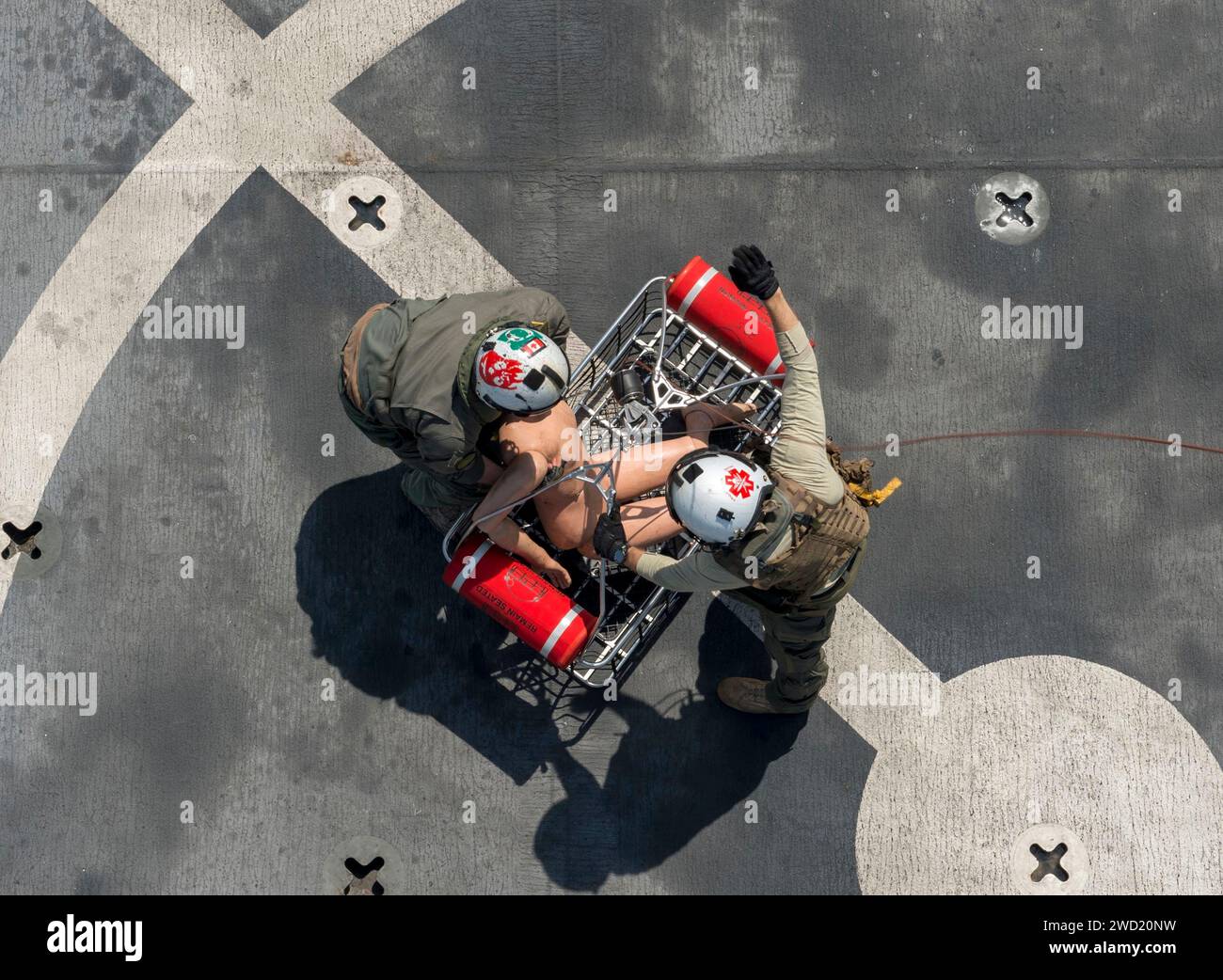 U.S. Navy Airmen load a training dummy into a rescue litter from an MH ...