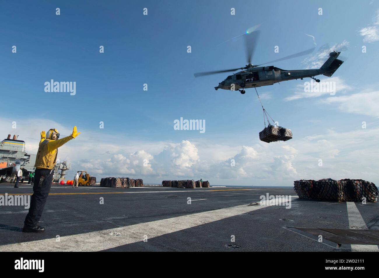 A U.S. Navy MH-60S Sea Hawk prepares to offload pallets of cargo onto ...