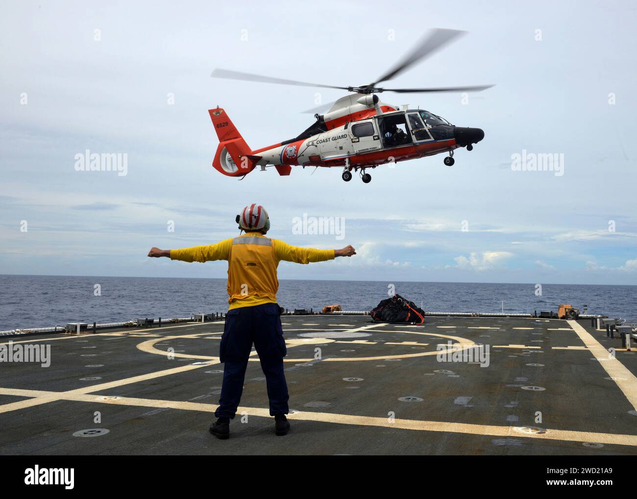 Crew members conduct flight operations with an HM-65 Dolphin helicopter ...