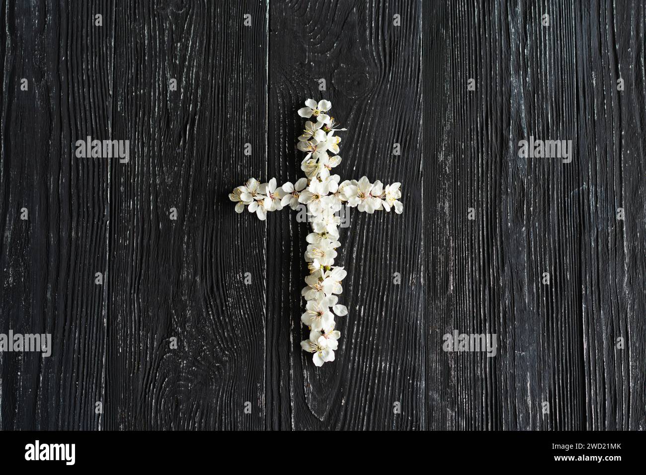 Cross with flowers on a wooden background with the inscription Christ ...