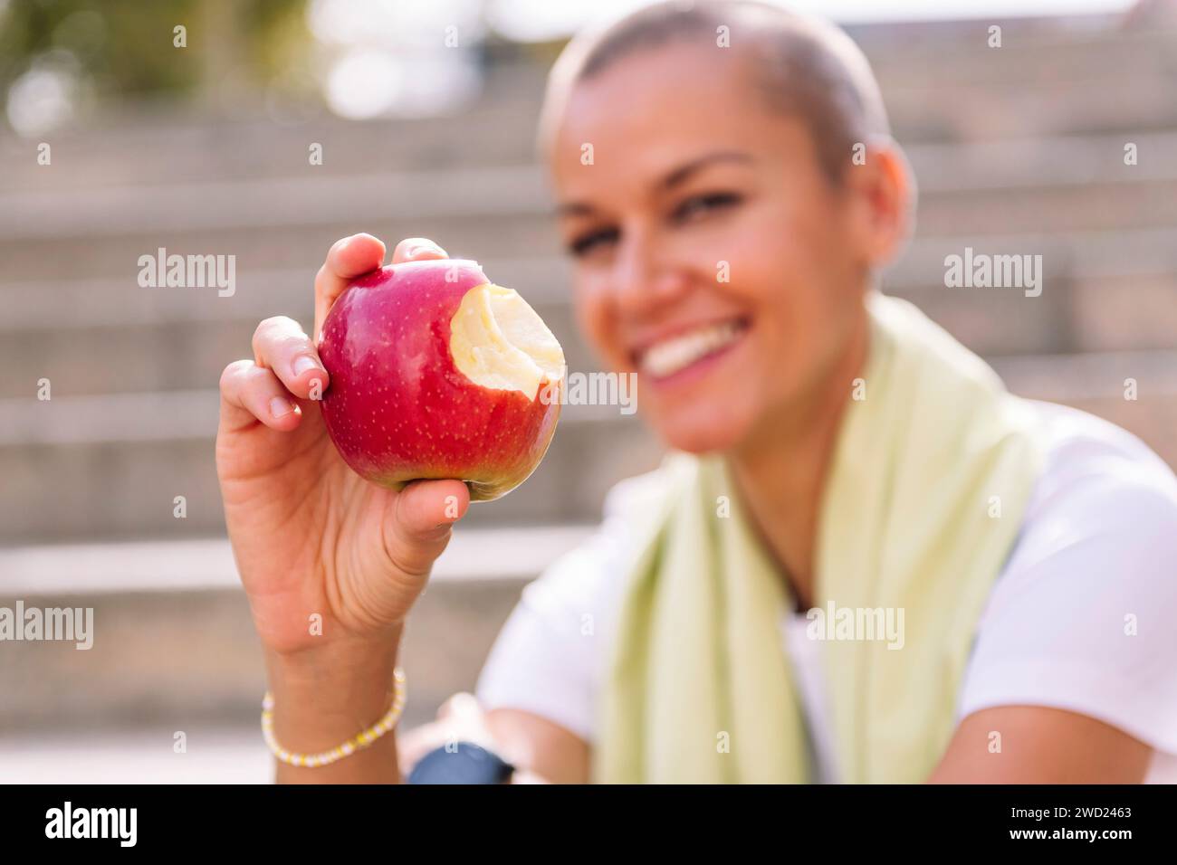 smiling sports woman showing a bitten apple Stock Photo - Alamy
