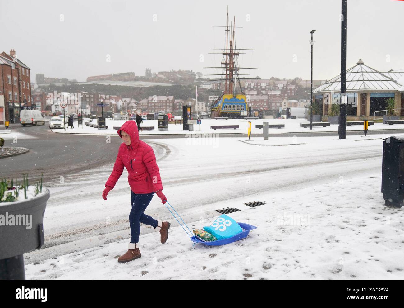 A person pulls a sled through snow in Whitby. Hundreds of schools are ...
