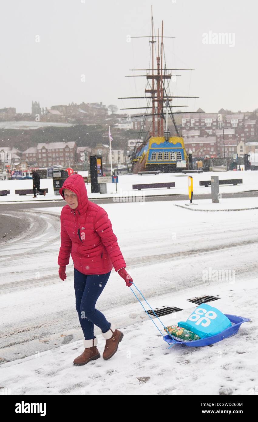 A person pulls a sled through snow in Whitby. Hundreds of schools are ...