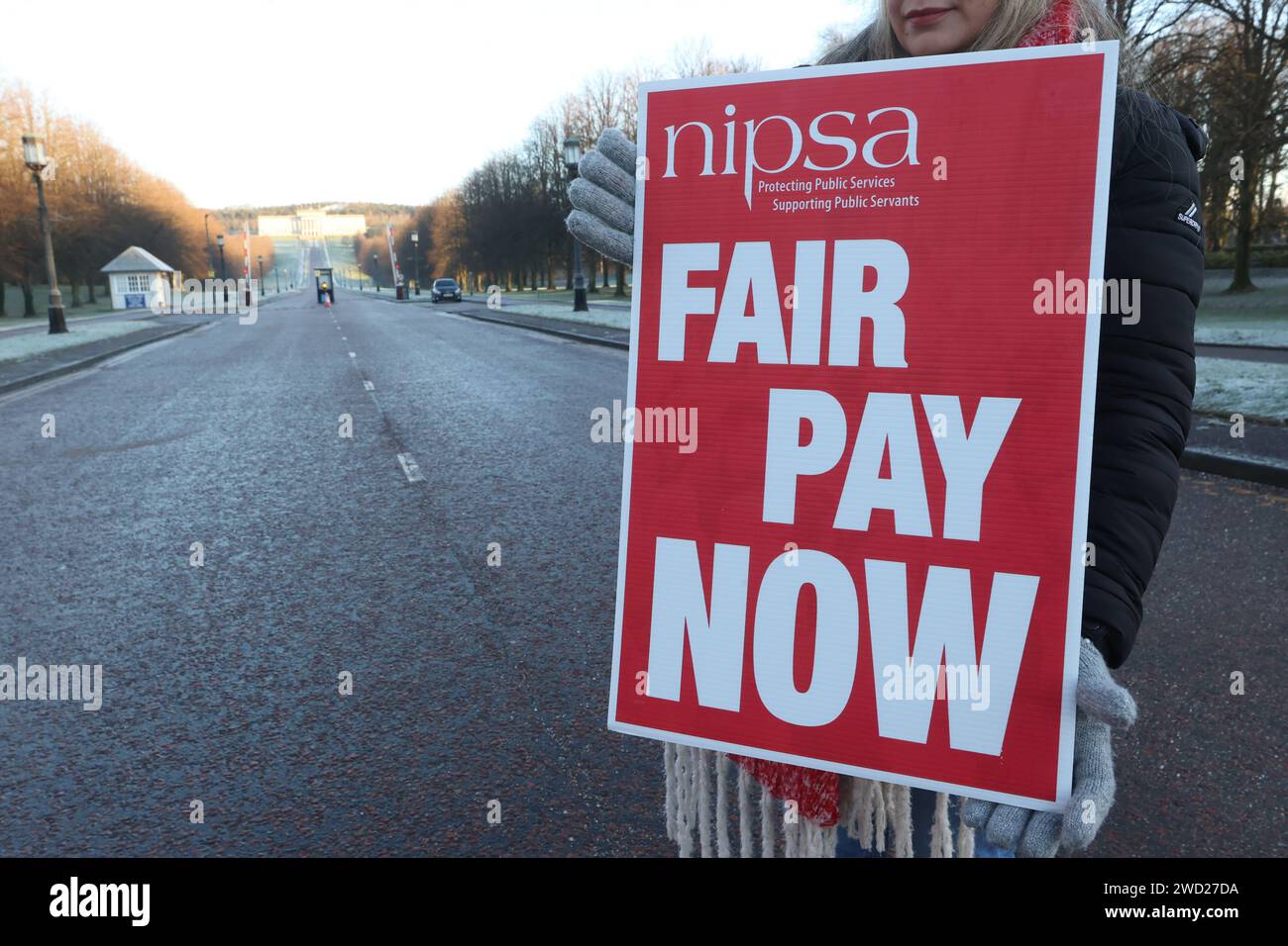 A woman holds up a "Fair Pay Now" sign on the picket line outside the ...
