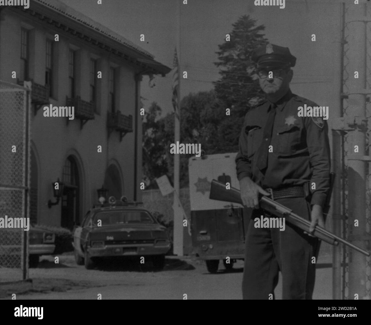 Officer George Benner stands guard with a shotgun at the gate leading ...