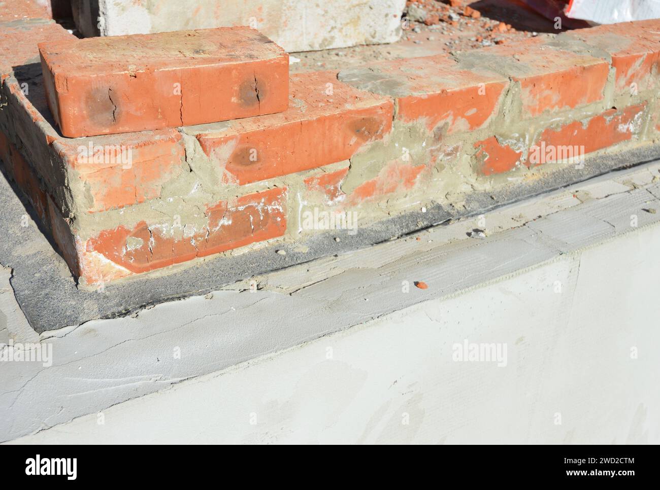 Laying bricks on the concrete foundation, footing, base covered with ...