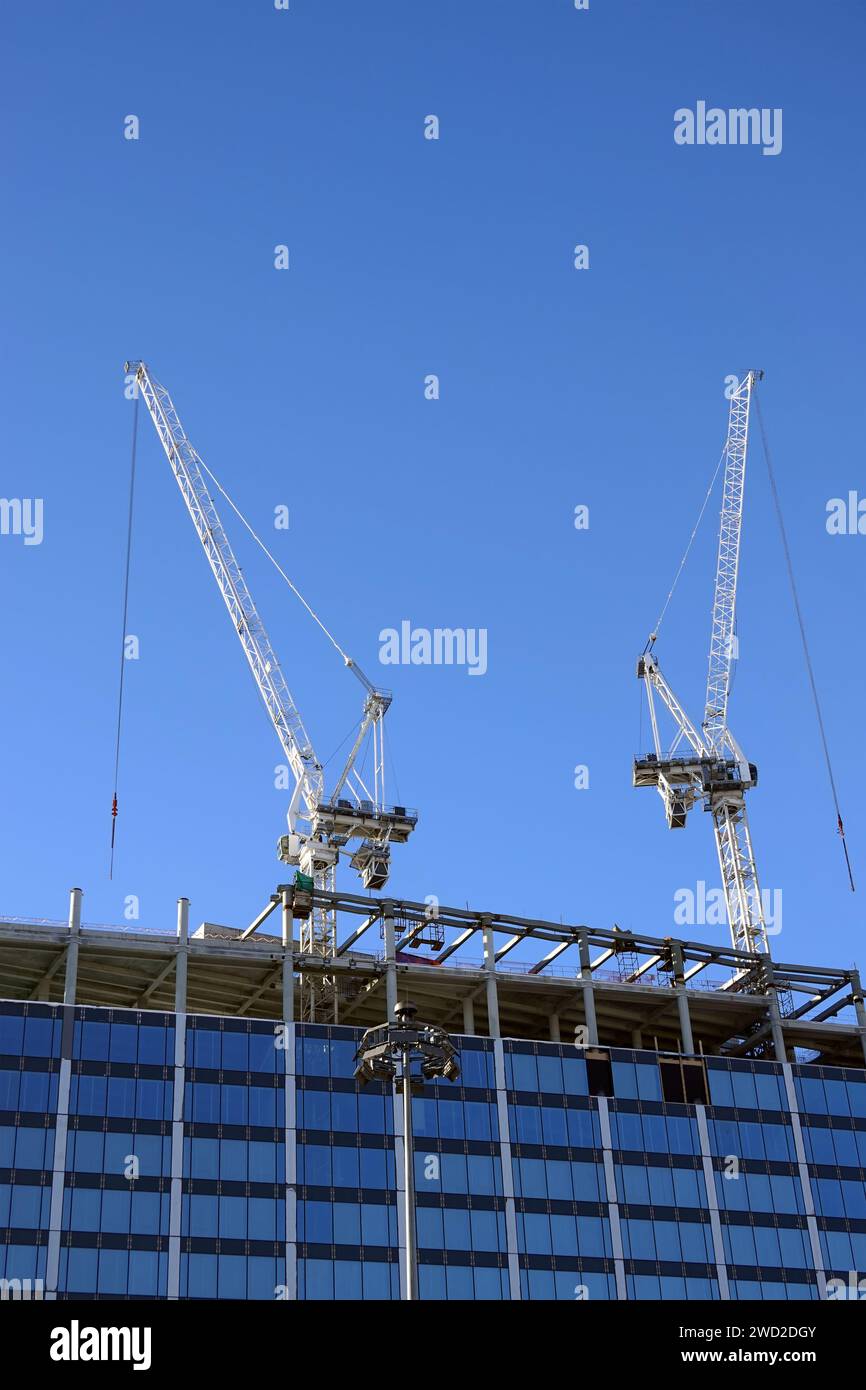 Two hoisting tower cranes on the roof of being construction of modern ...
