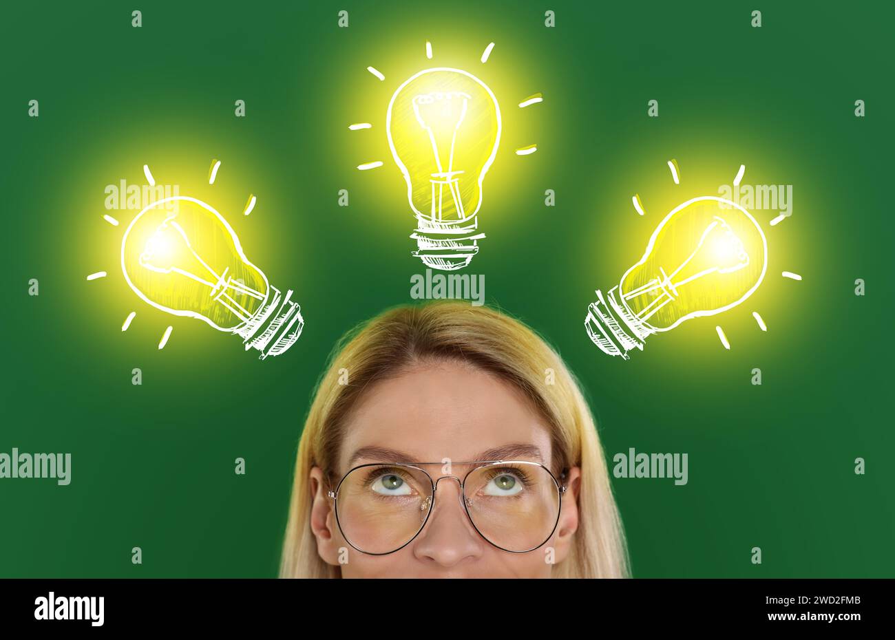 Idea generation. Woman looking at illustrations of glowing light bulb ...