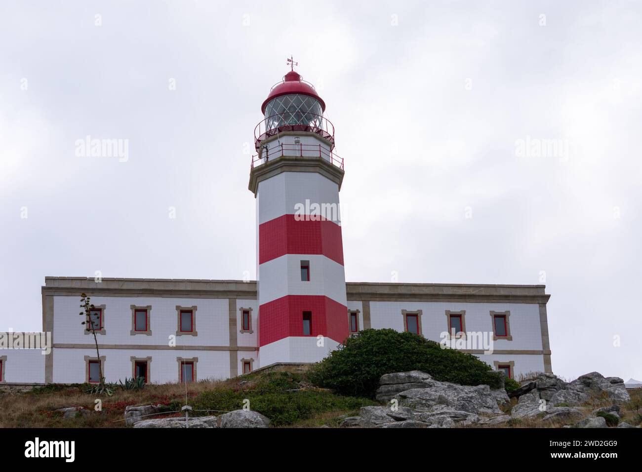 The Cabo Silleiro lighthouse with its red stripes on the rocky mountain ...