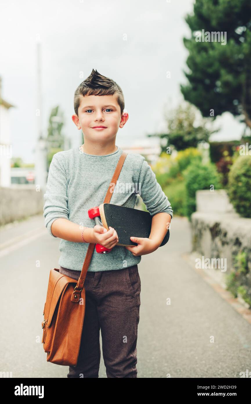 Outdoor portrait of funny little schoolboy wearing brown leather bag ...
