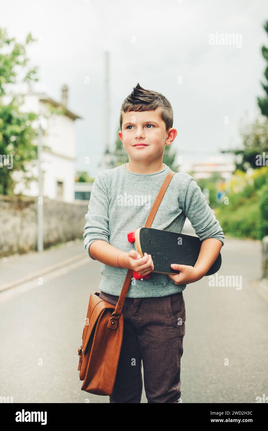 Outdoor portrait of funny little schoolboy wearing brown leather bag ...