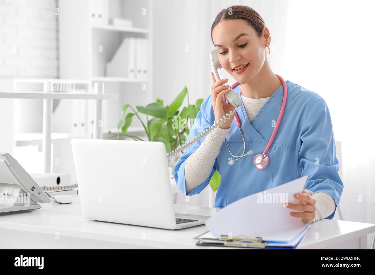 Female medical intern talking by telephone in clinic Stock Photo - Alamy