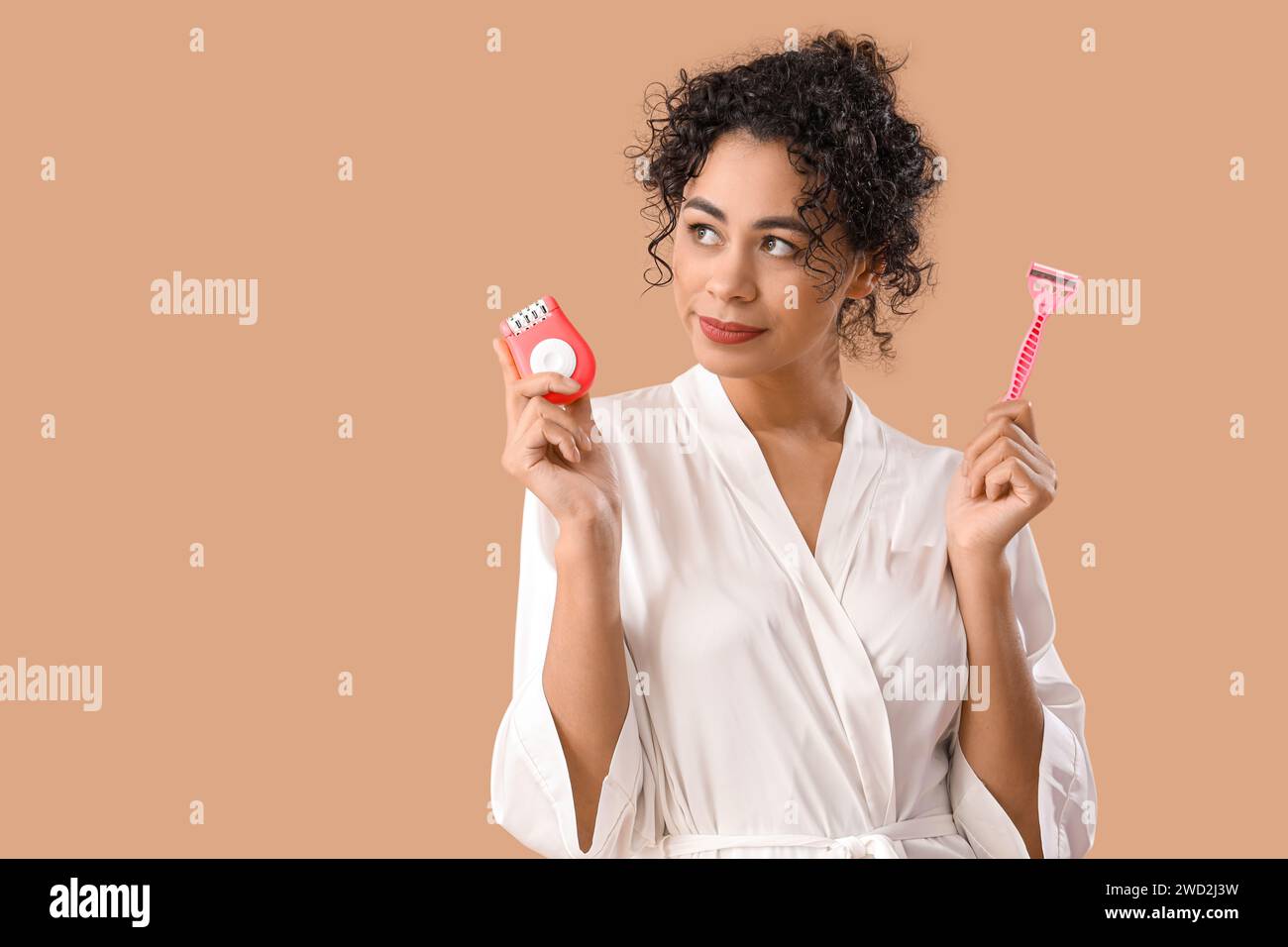 Beautiful African-American woman choosing between epilator and razor on ...