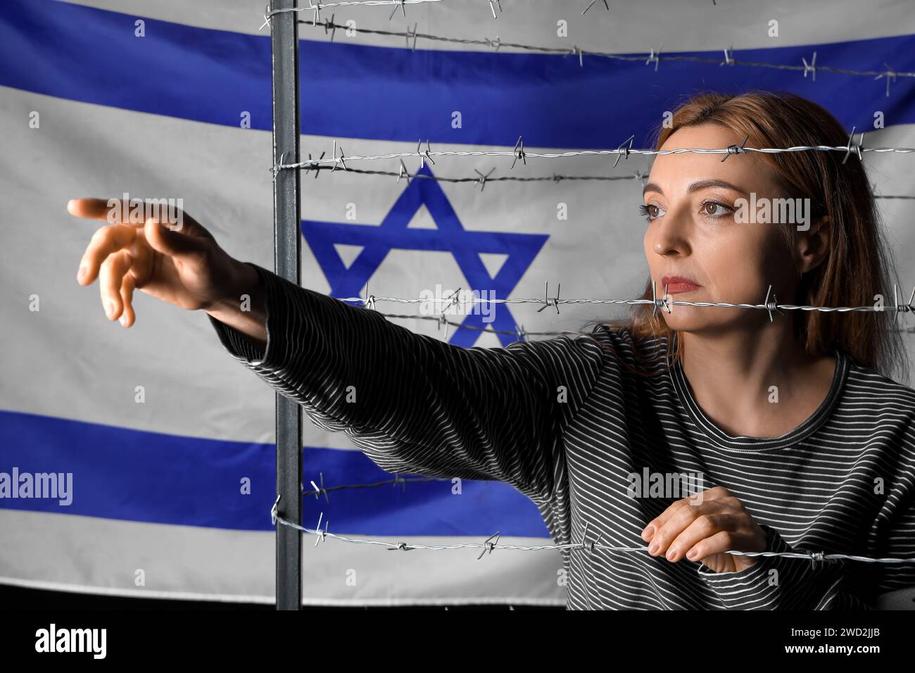 Mature woman behind barbed wire against flag of Israel. International ...