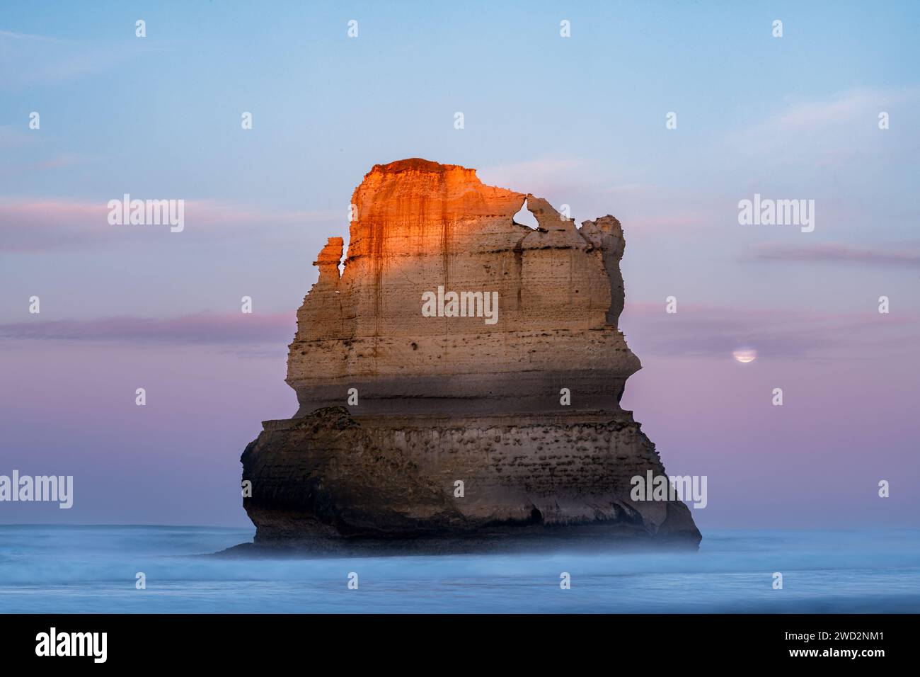 First light on a sea stack of the Twelve Apostles while the full moon ...
