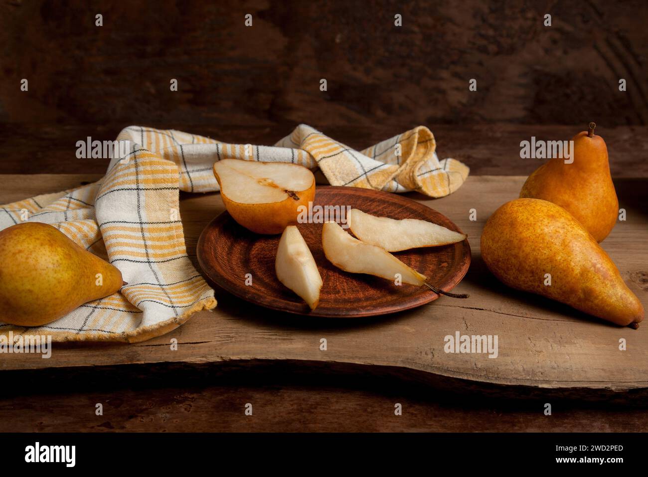 Clay plate with half and slices of ripe juicy pear fruits and clay ...