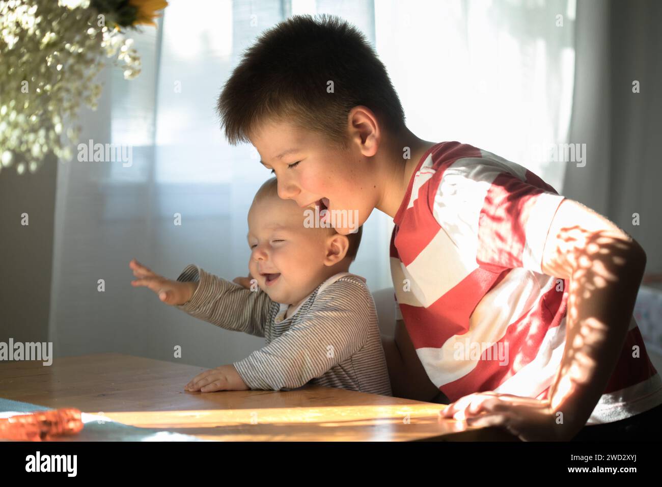 Older brother kissing and hugging his baby boy. Two siblings. Beautiful ...