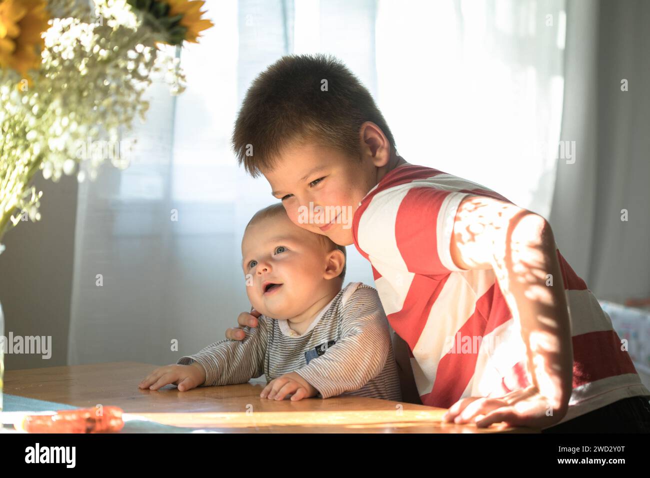 Older brother kissing and hugging his baby boy. Two siblings. Beautiful ...